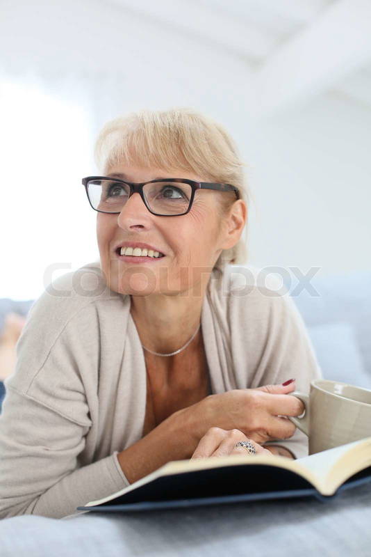 Senior Woman Reading Book And Relaxing In Sofa Colourbox
