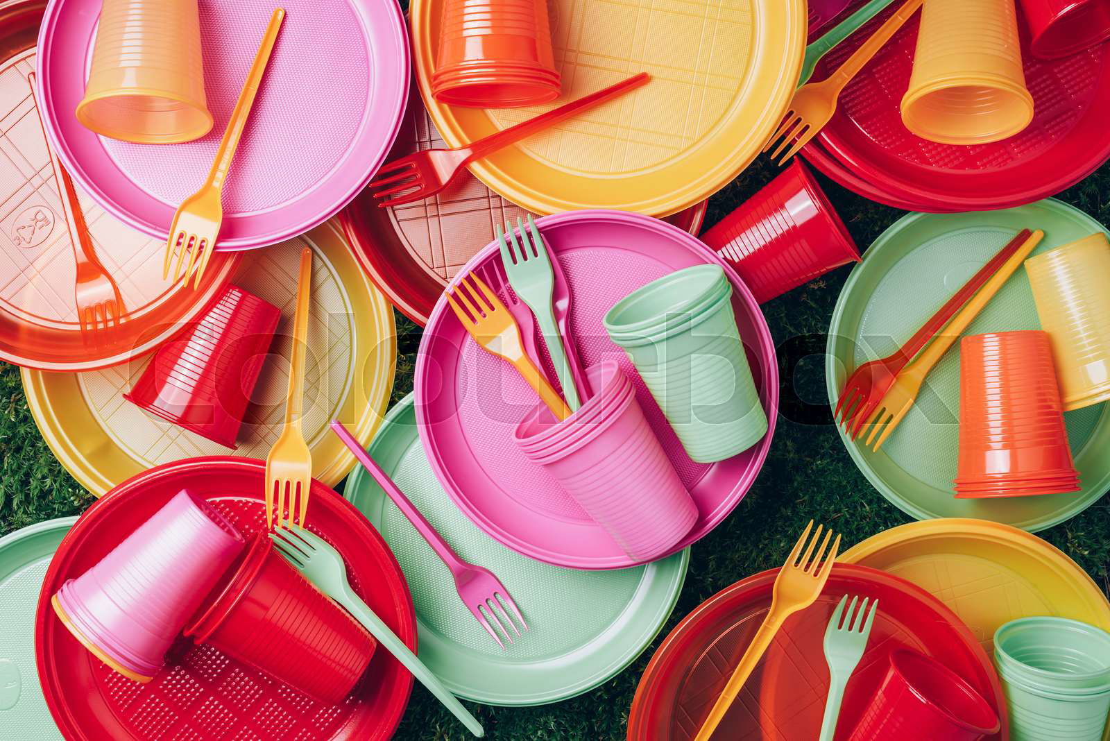 Colored plastic disposable tableware on green grass moss bac Colourbox