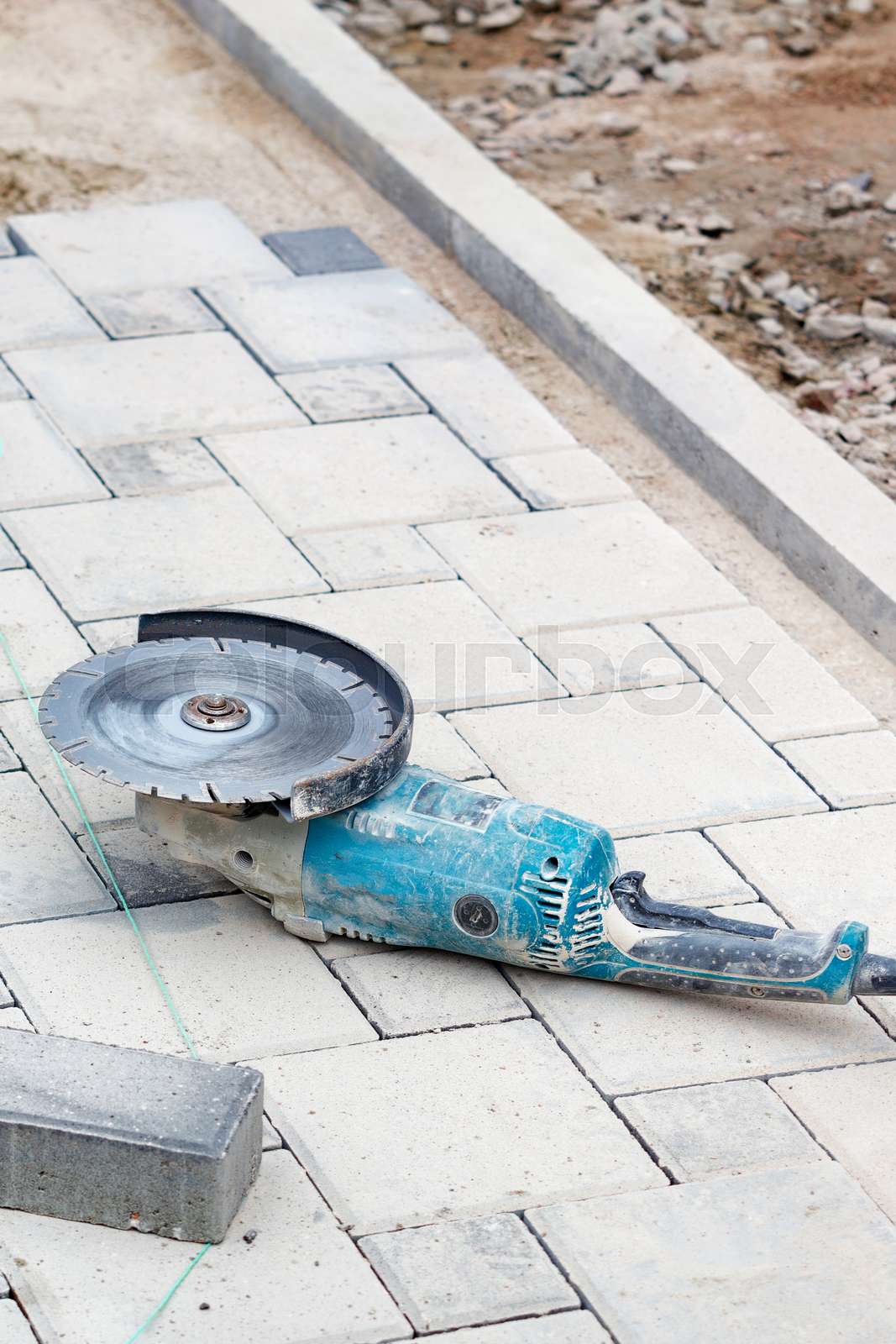 A worn out diamond angle grinder lies on the paving slabs in Colourbox